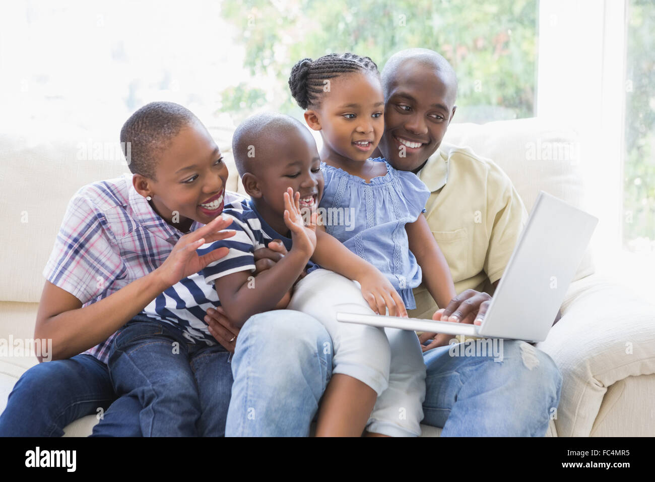 Happy family on the couch chatting with laptop Stock Photo - Alamy