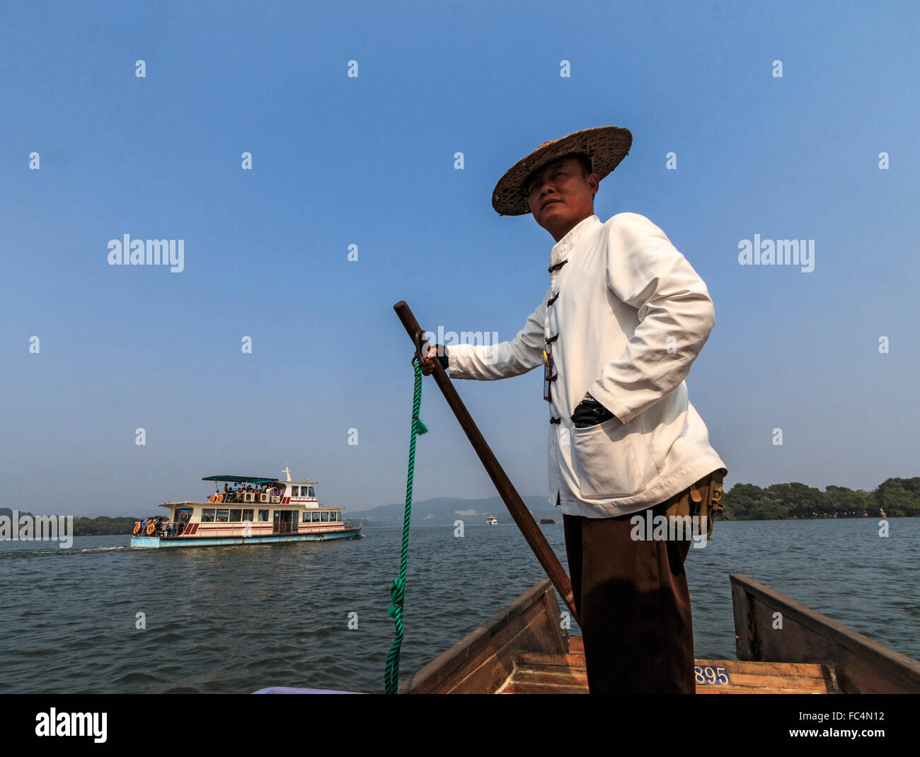 Boatman rows boat during tour on Hangzhou's West Lake. Tour boats ...