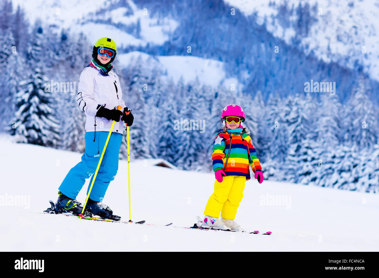 Boy and girl skiing in mountains. Toddler kid and teenager with helmet ...