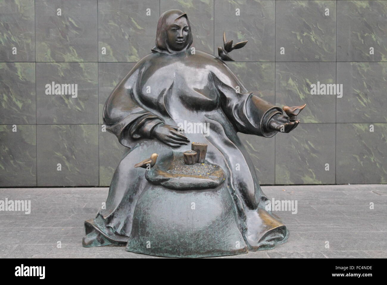 bronze statue of fat trade woman sit and feed birds from hands,Septemer ...
