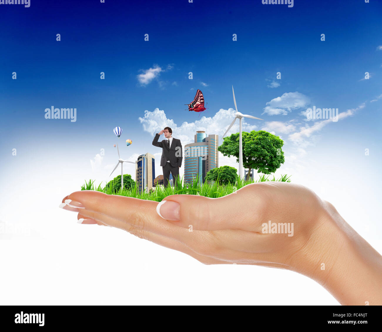 human hand holding a city on green grass hill Stock Photo - Alamy