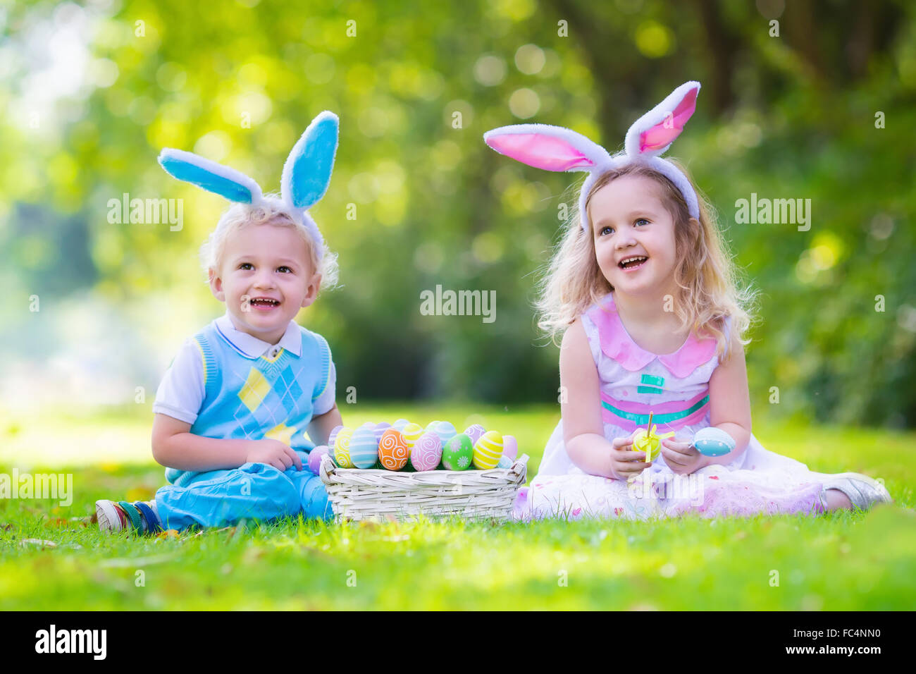 Little boy and girl having fun on Easter egg hunt. Kids in bunny ears ...