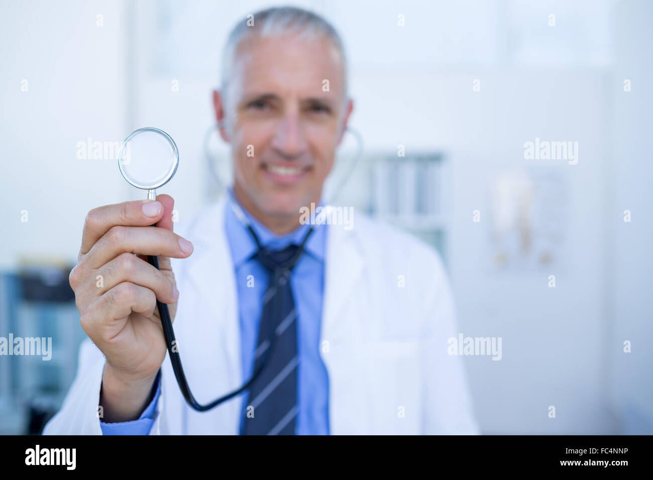 Happy doctor smiling at camera and showing his stethoscope Stock Photo ...