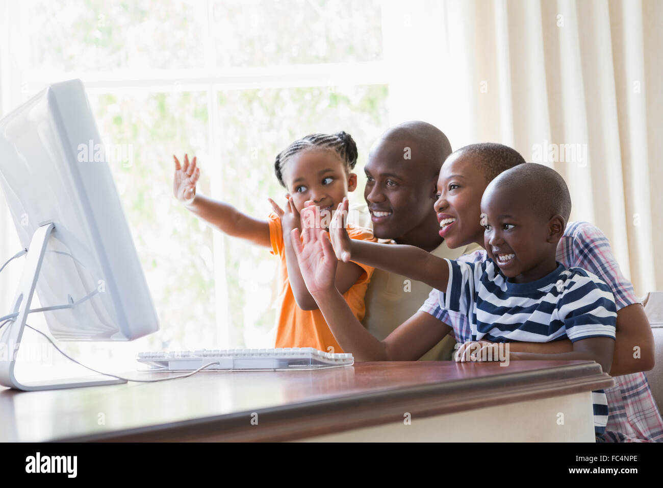 Happy smiling family chatting with computer together Stock Photo - Alamy