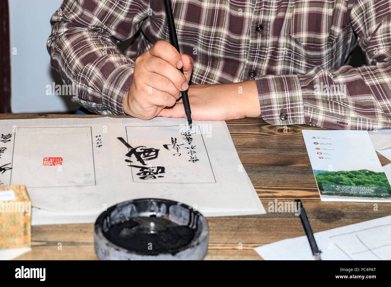 Wang Zhen, a master engraver, finishes up a scroll for a student ...