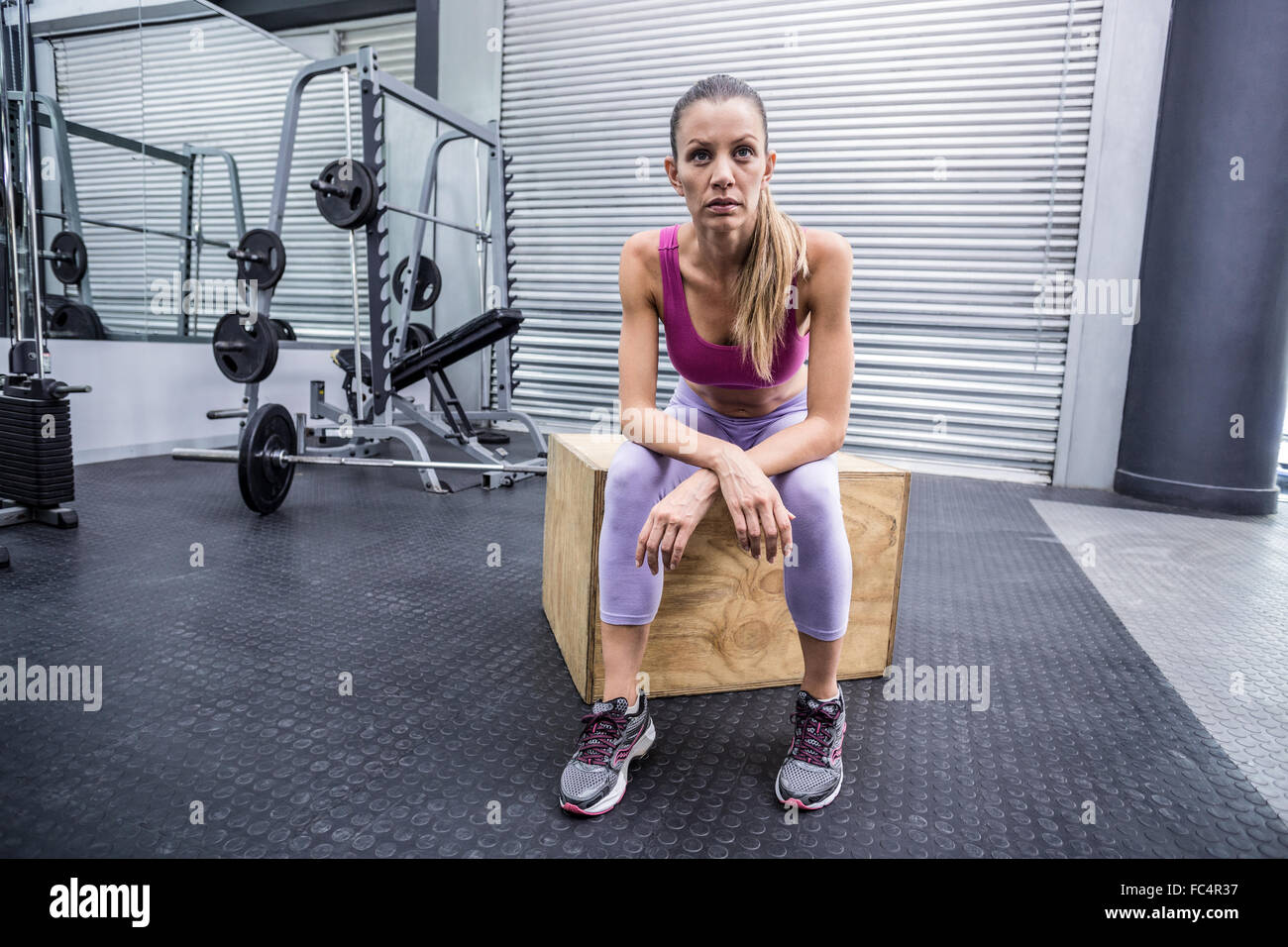 Serious muscular woman sitting on a wooden box Stock Photo - Alamy