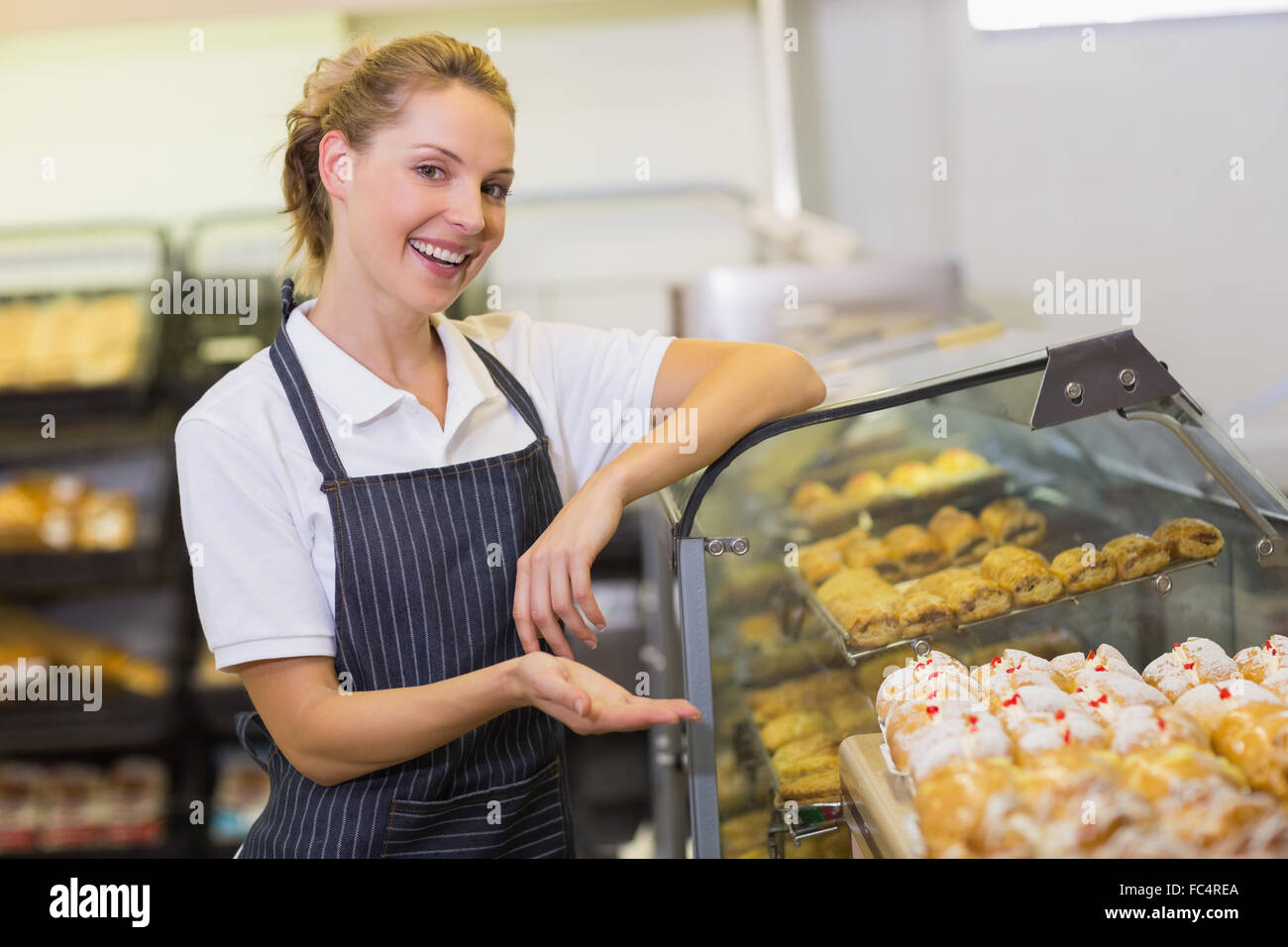 Portrait of a smiling blonde baker showing a pastry Stock Photo - Alamy