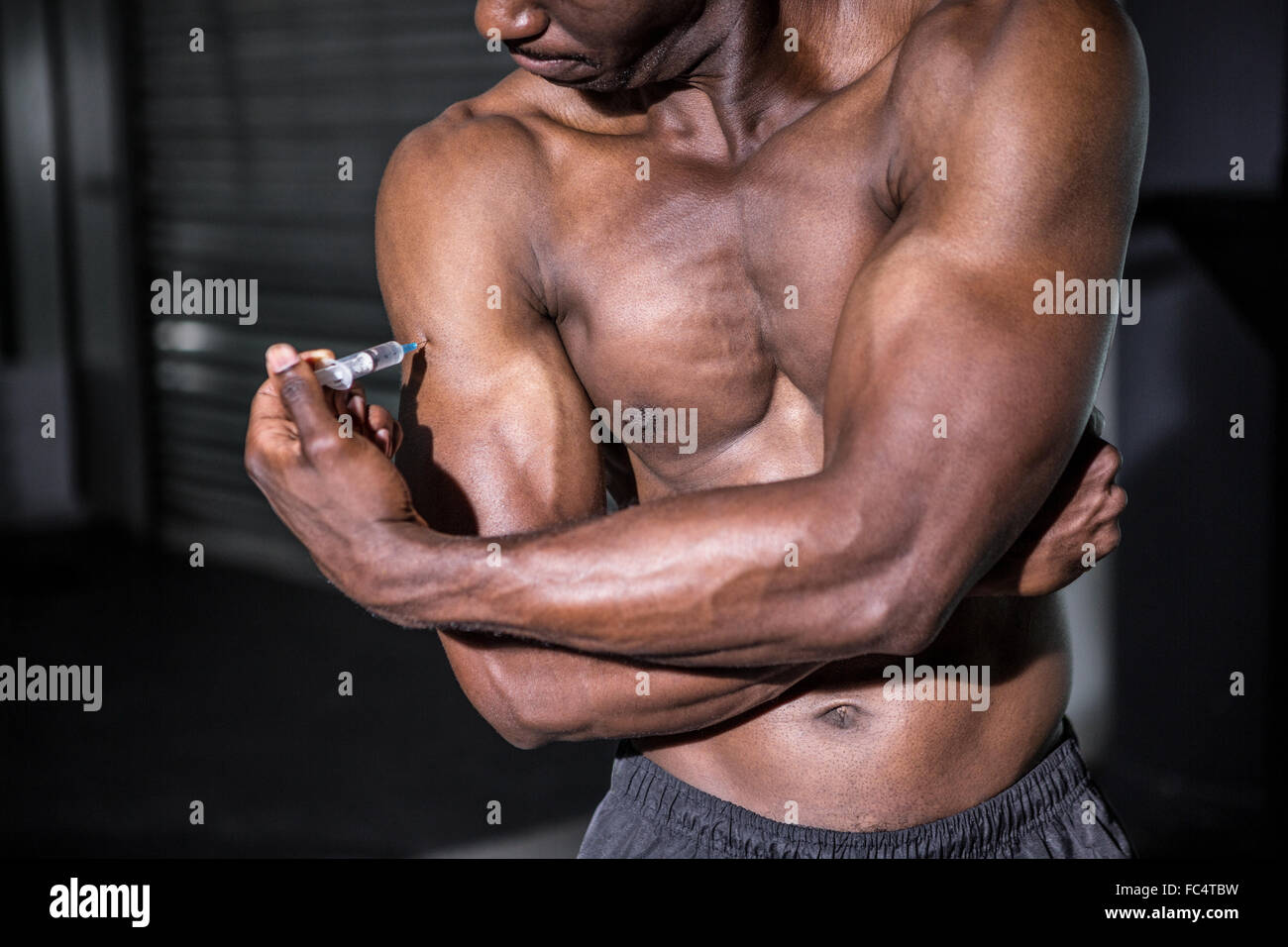 Young Bodybuilder injecting something into his arm Stock Photo - Alamy