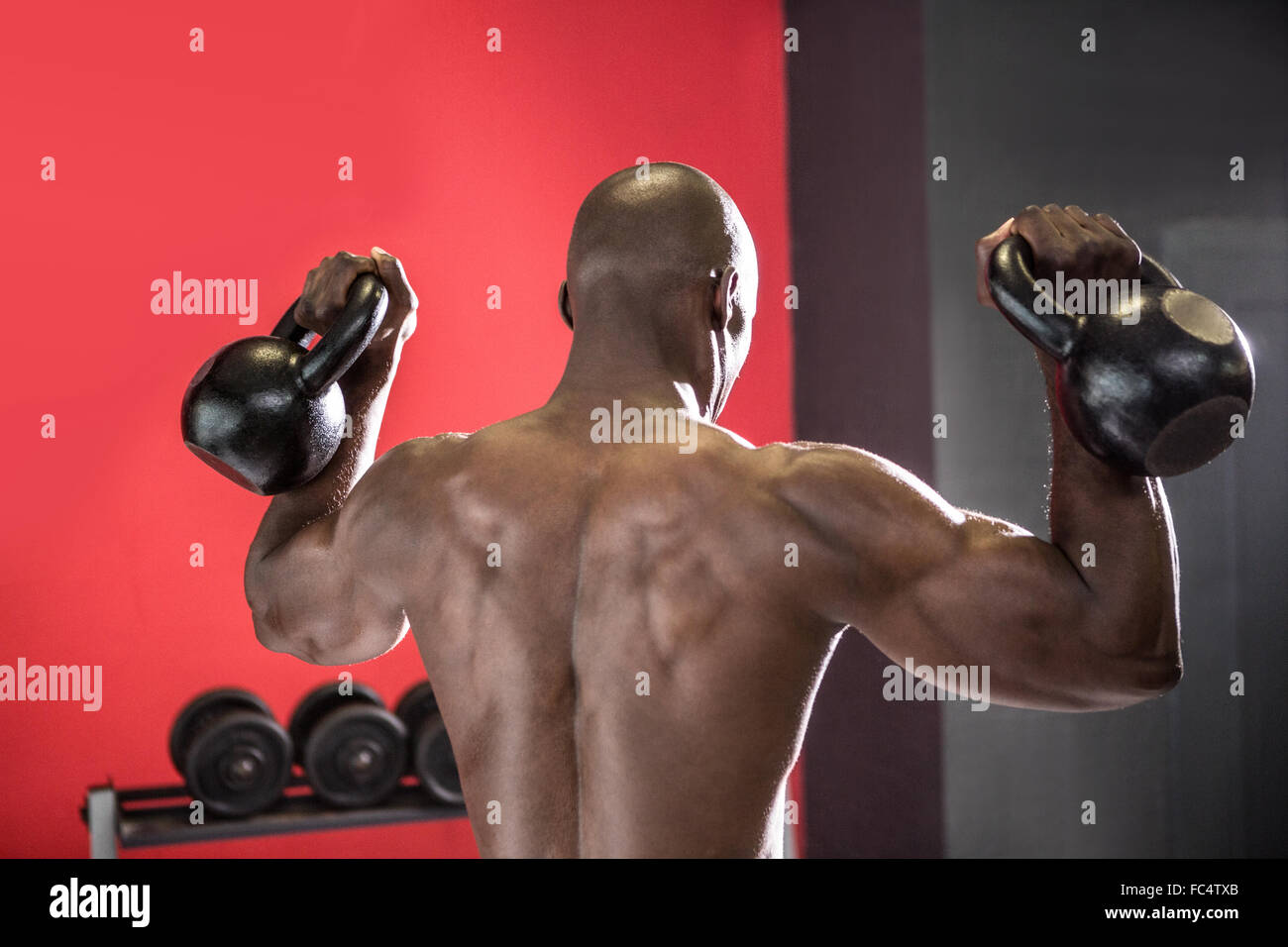 Back view of muscular man lifting two kettlebells Stock Photo - Alamy