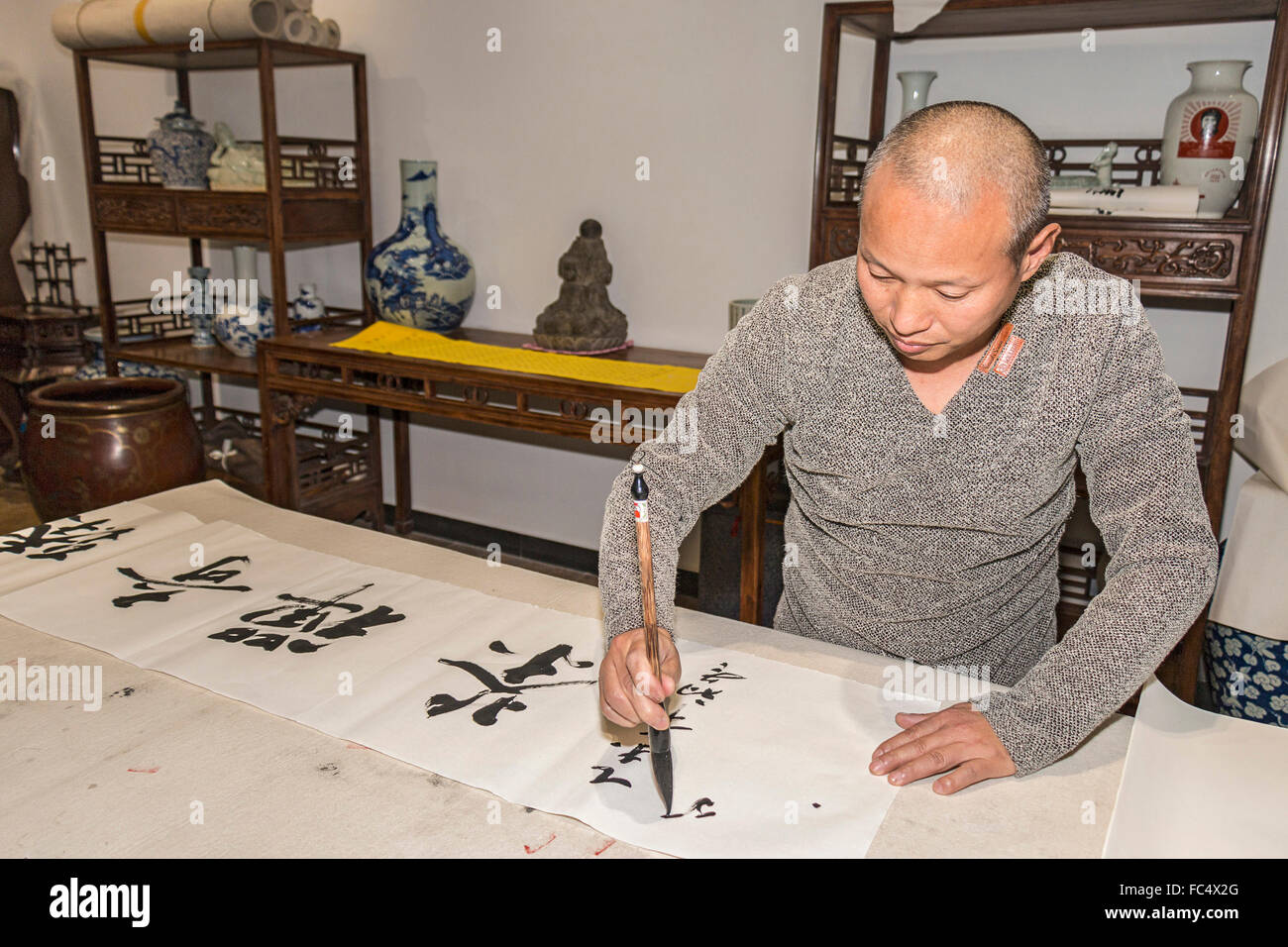 Calligrapher writing Chinese symbols on scroll at Zhen Qi Hui Art ...