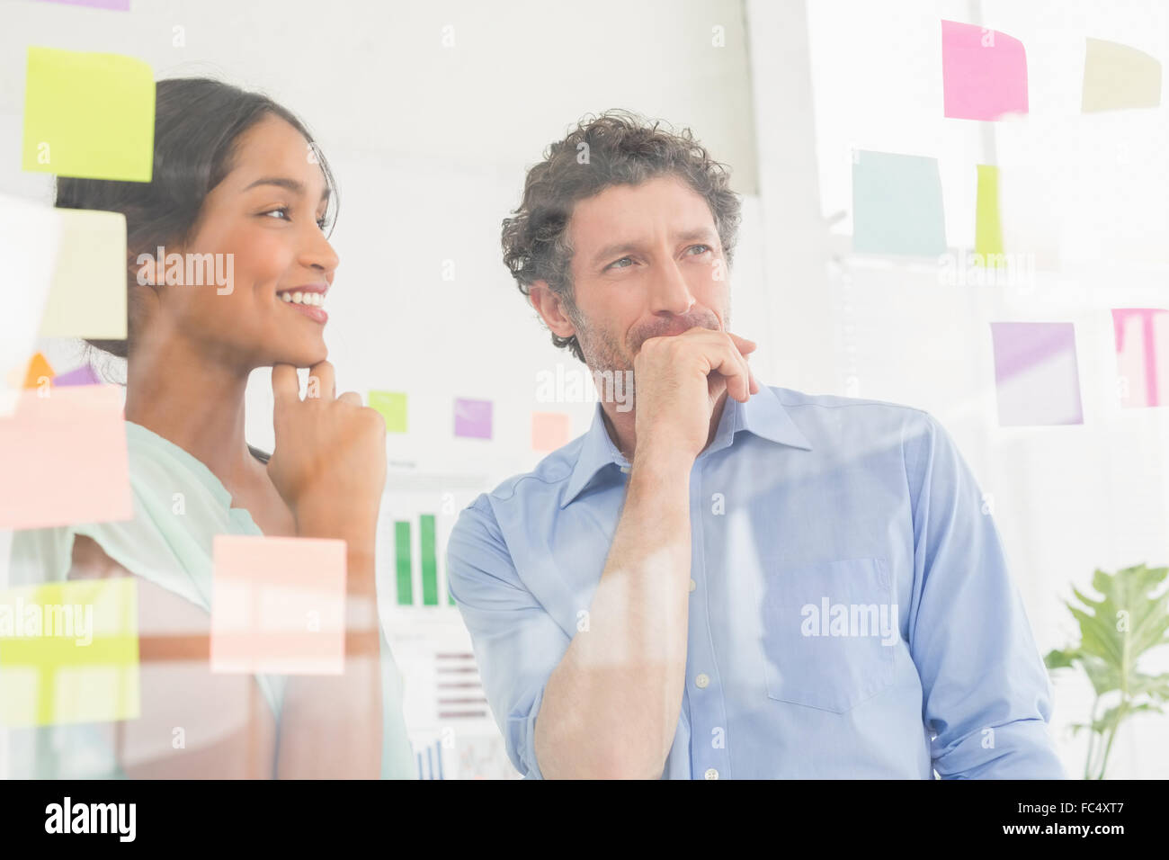 Puzzled business team looking post its on the wall Stock Photo - Alamy