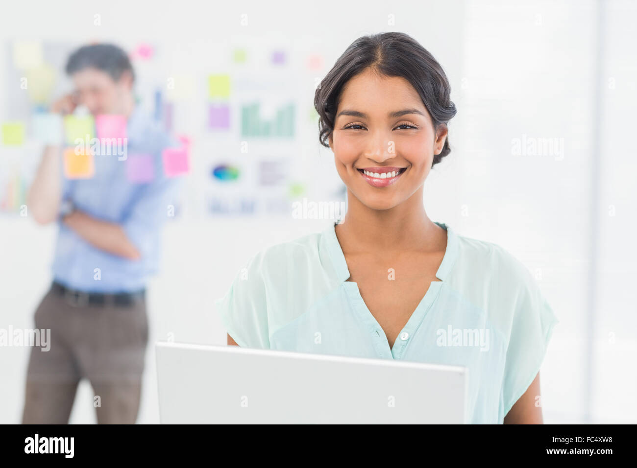 Businesswoman presenting laptop screen with colleague behind her Stock ...