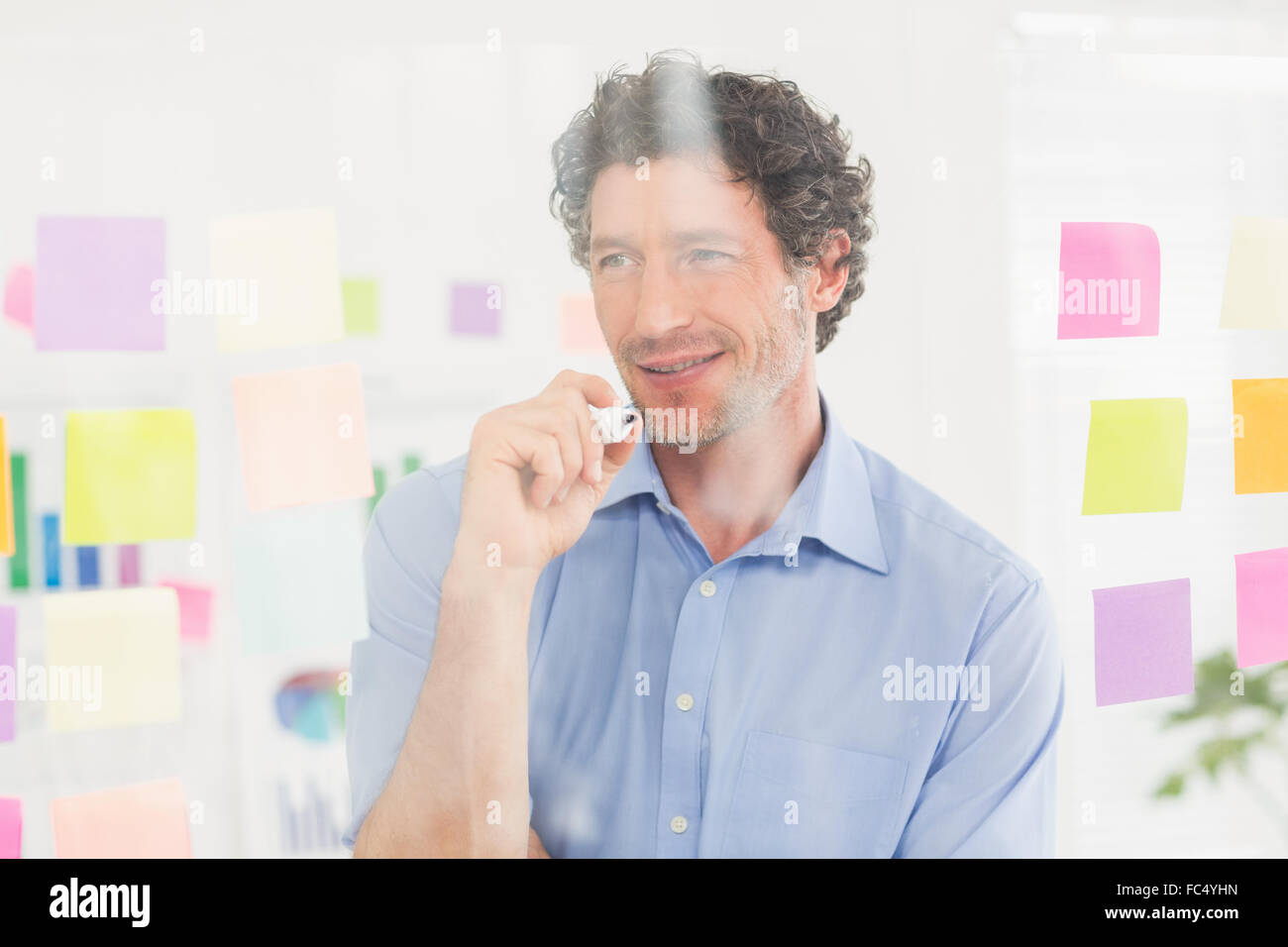 Puzzled businessman looking post its on the wall Stock Photo - Alamy