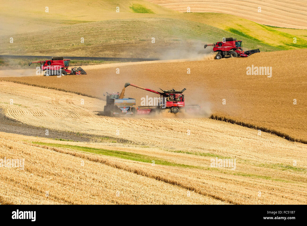 One or more combines offloading grain to a tractor pulled grain cart in ...