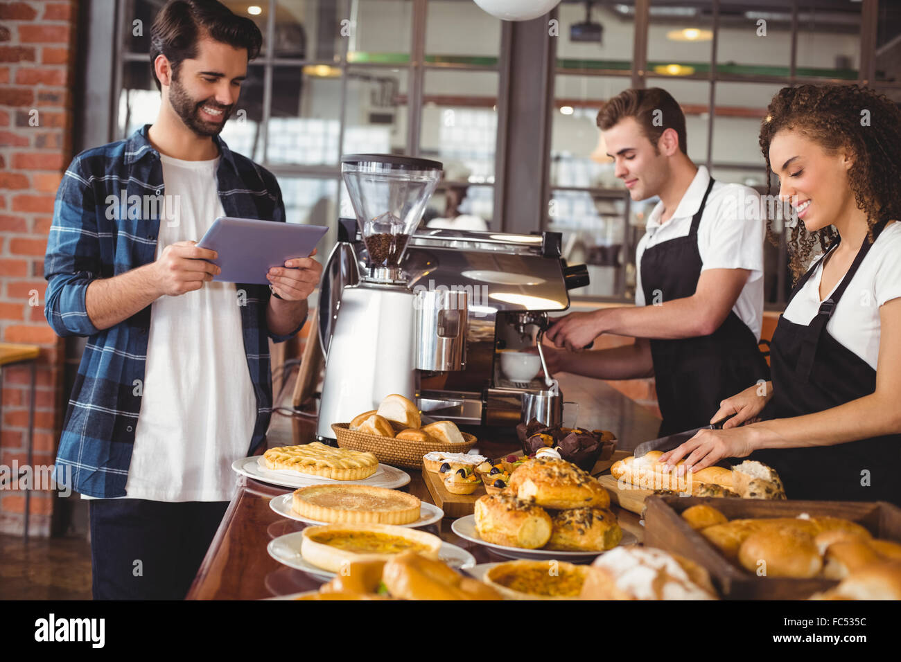 Smiling colleagues serving customer with tablet Stock Photo - Alamy