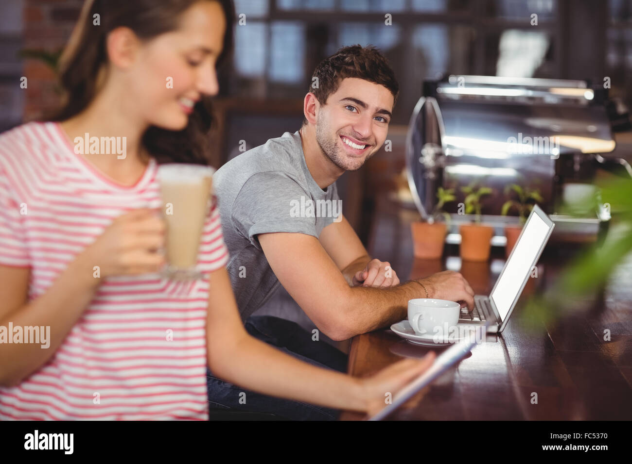 Smiling young man sitting at bar and using laptop Stock Photo - Alamy