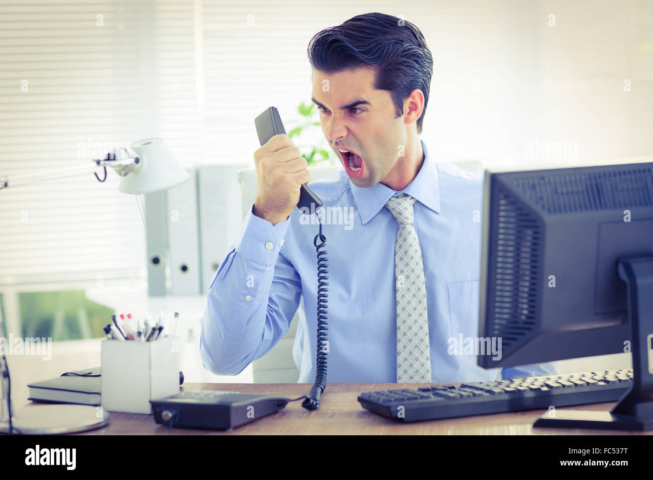 Businessman shouting as he holds out phone at office Stock Photo - Alamy