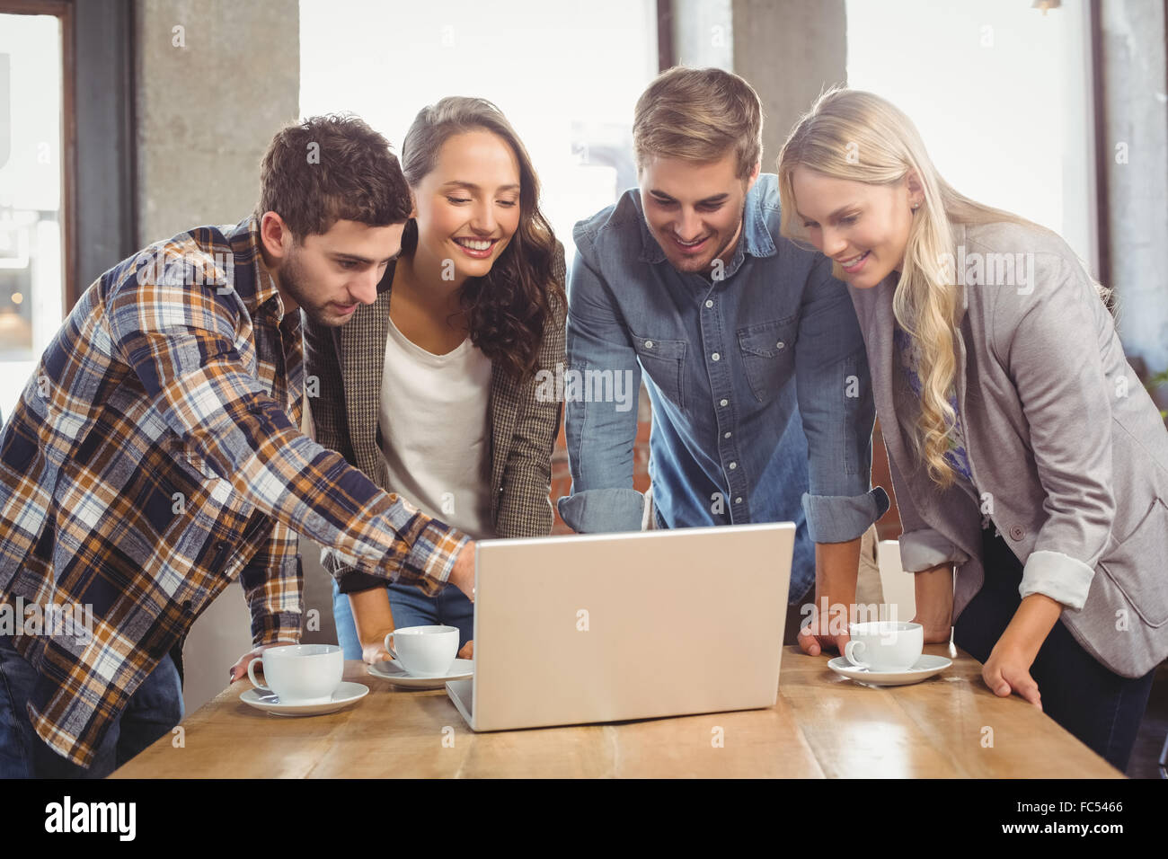 Smiling friends standing and pointing on laptop screen Stock Photo - Alamy