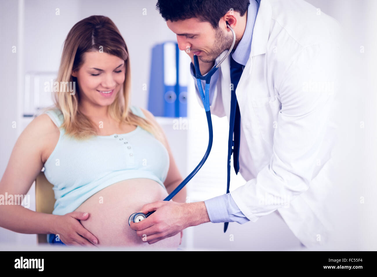 Smiling doctor examining stomach of pregnant patient Stock Photo - Alamy