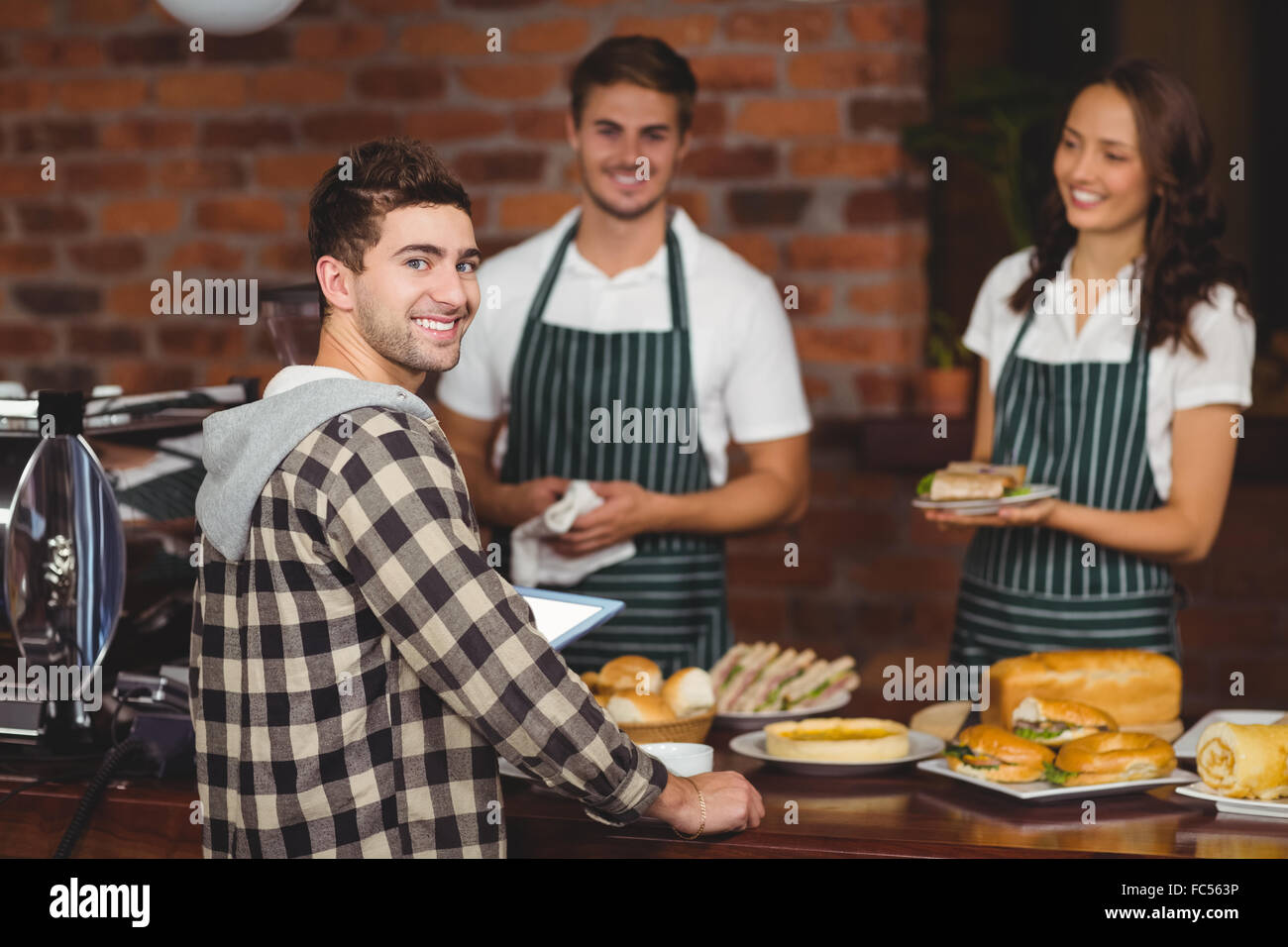Smiling waiters and customer looking at the camera Stock Photo - Alamy