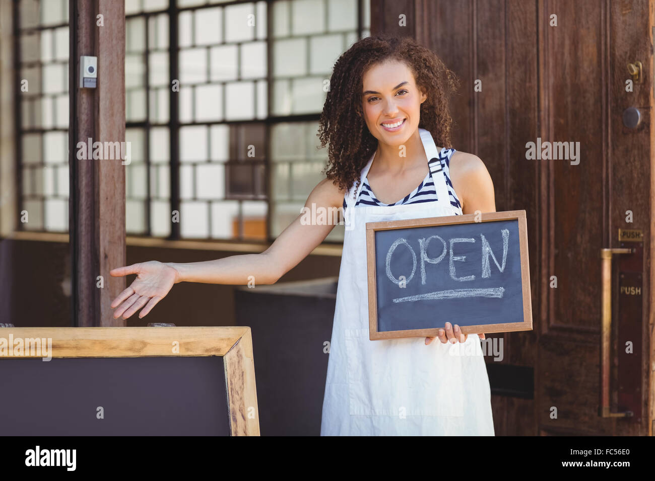 Smiling waitress showing chalkboard with open sign Stock Photo - Alamy