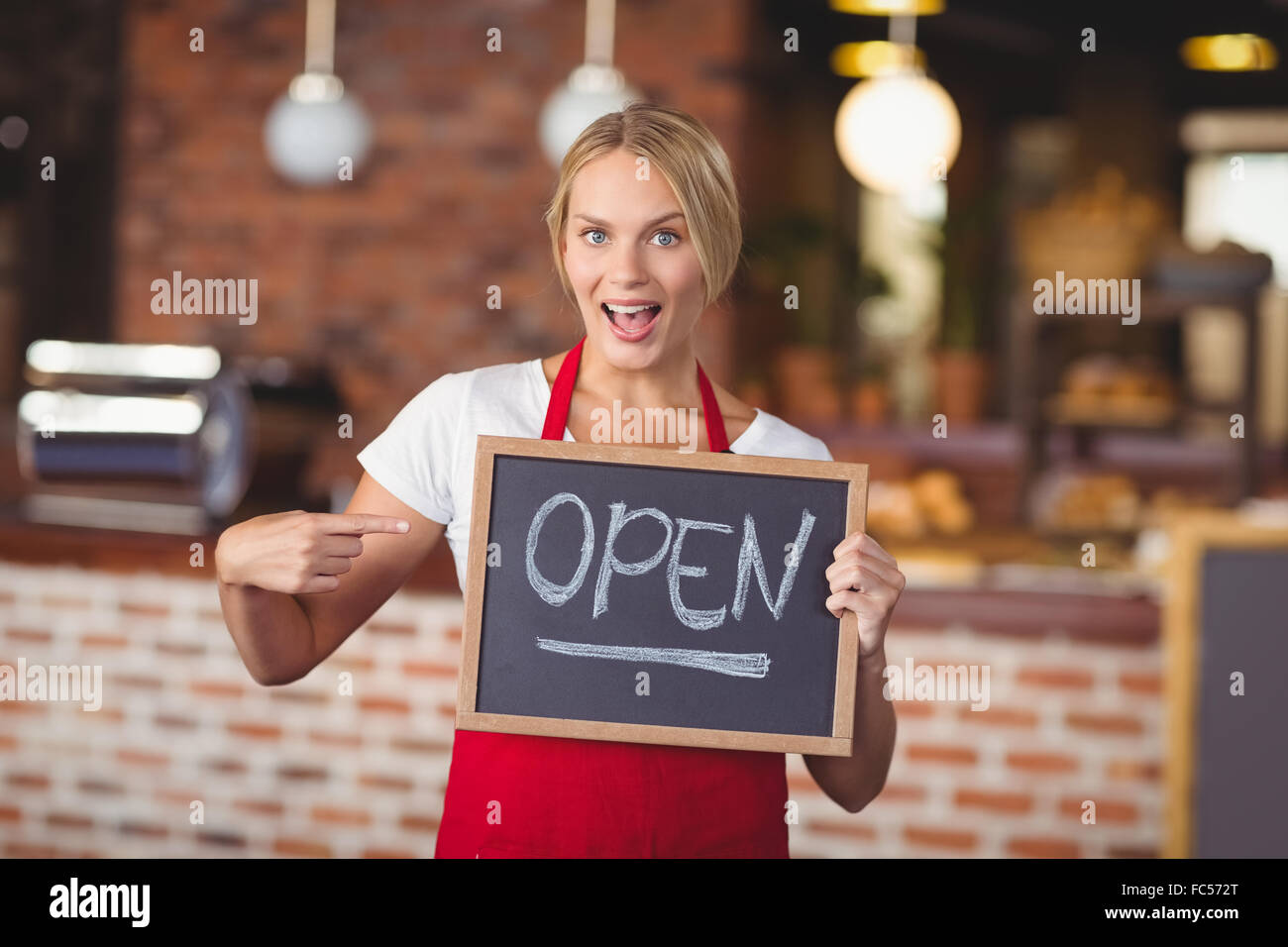 Pretty waitress pointing the chalkboard open sign Stock Photo - Alamy
