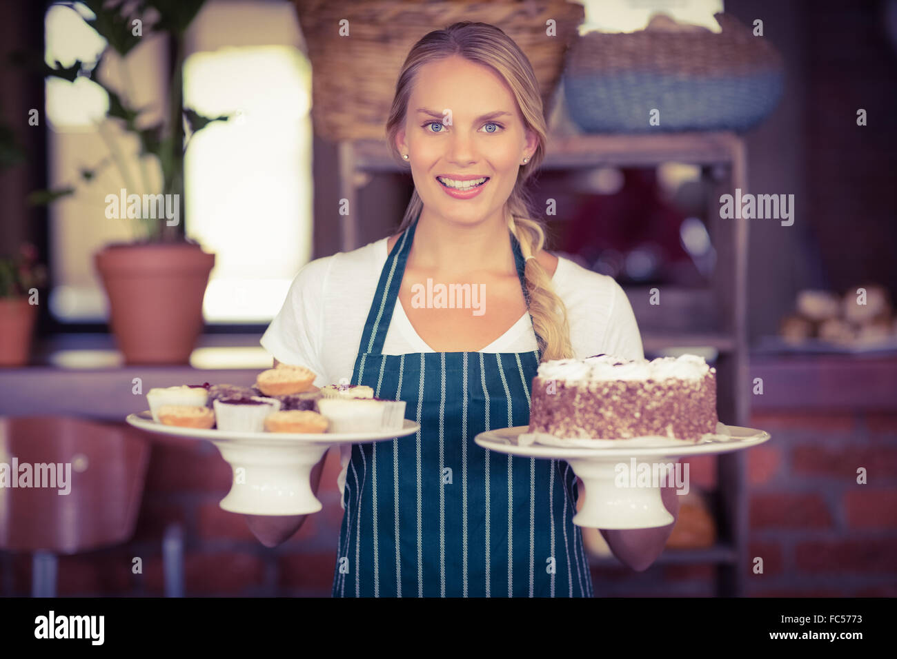 Pretty waitress holding a chocolate cake and cupcakes Stock Photo - Alamy