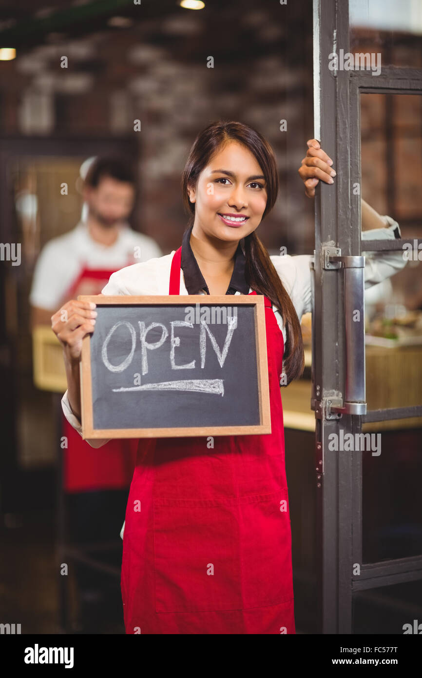 Smiling waitress showing chalkboard with open sign Stock Photo - Alamy