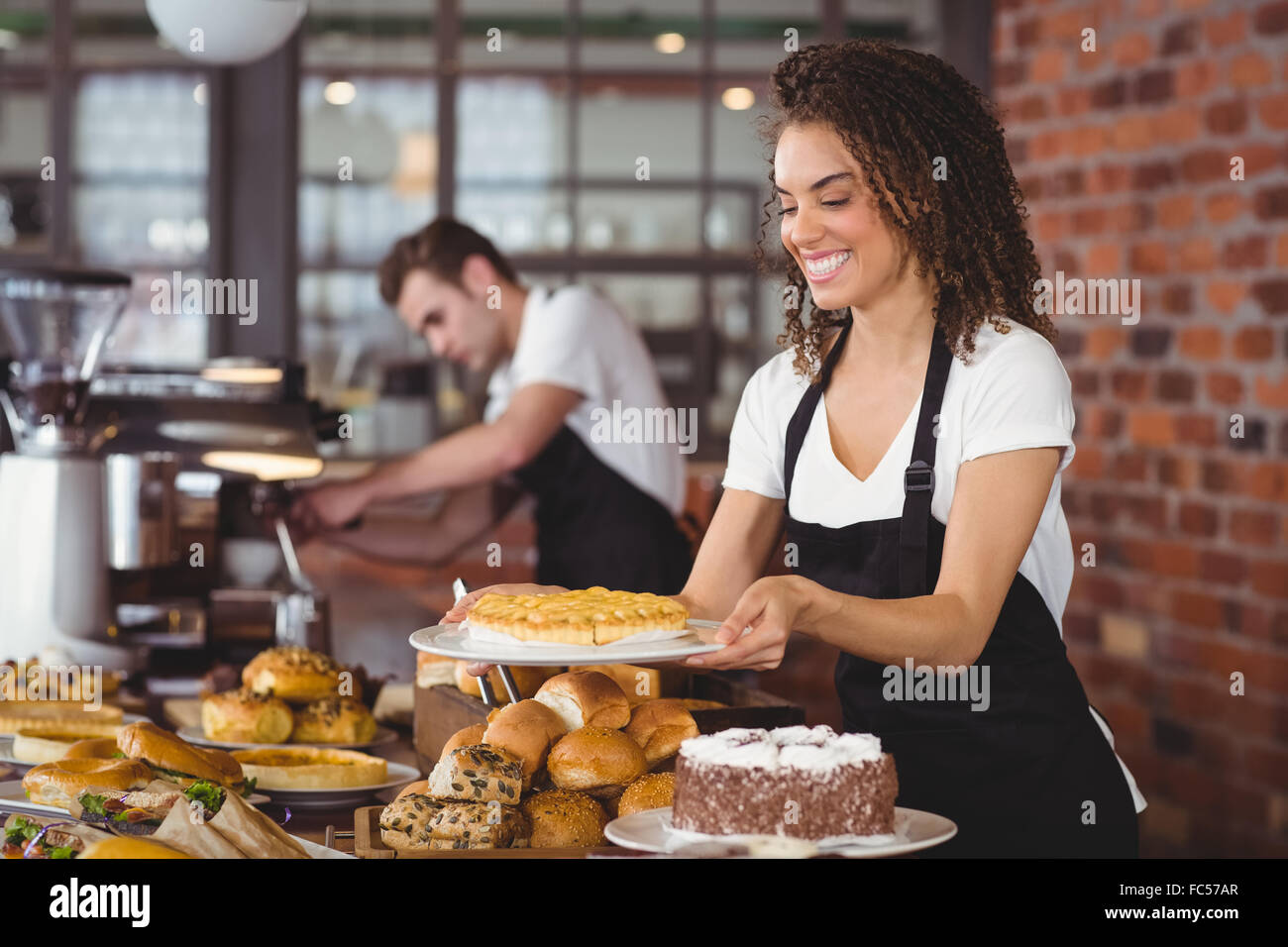 Smiling waitress holding cake in front of colleague Stock Photo - Alamy