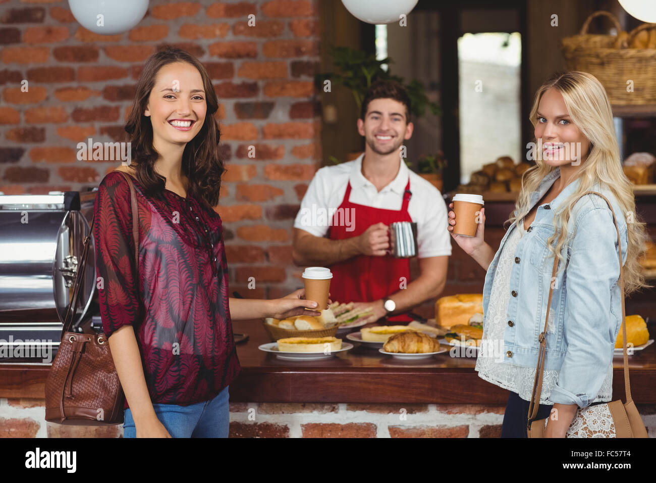 Smiling waiter and two customers looking at the camera Stock Photo - Alamy
