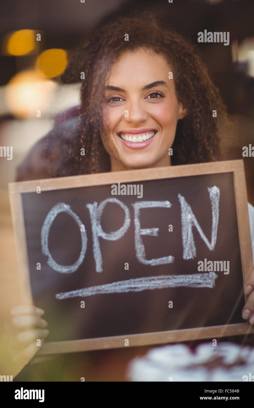 Smiling waitress showing chalkboard with open sign Stock Photo - Alamy