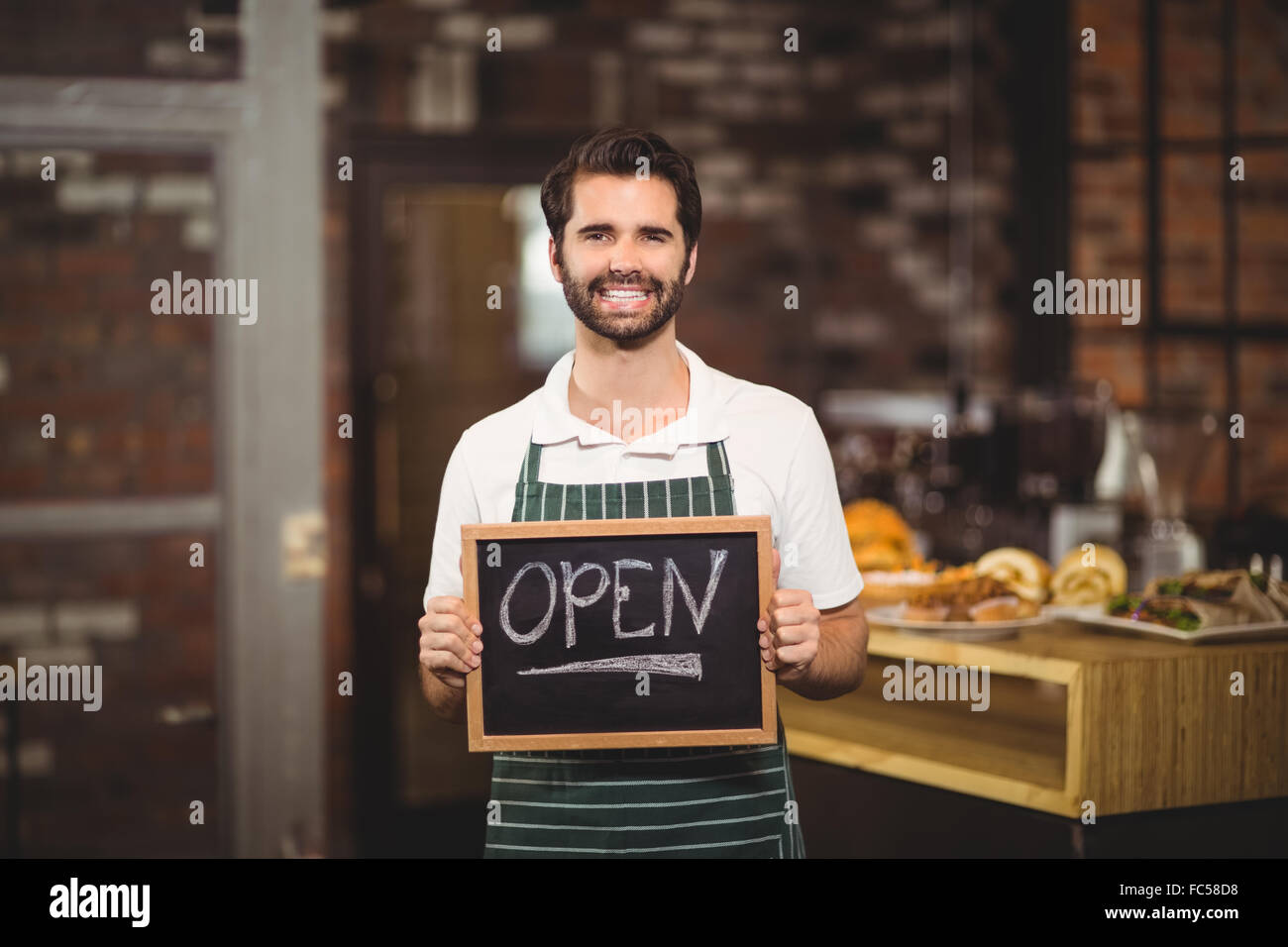 Smiling waiter showing chalkboard with open sign Stock Photo - Alamy