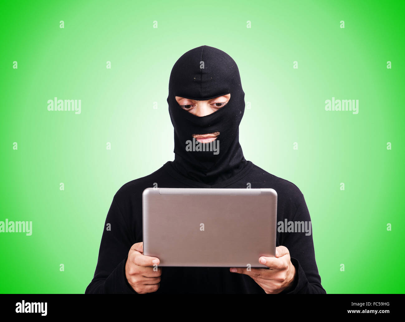 Hacker with computer wearing balaclava Stock Photo - Alamy