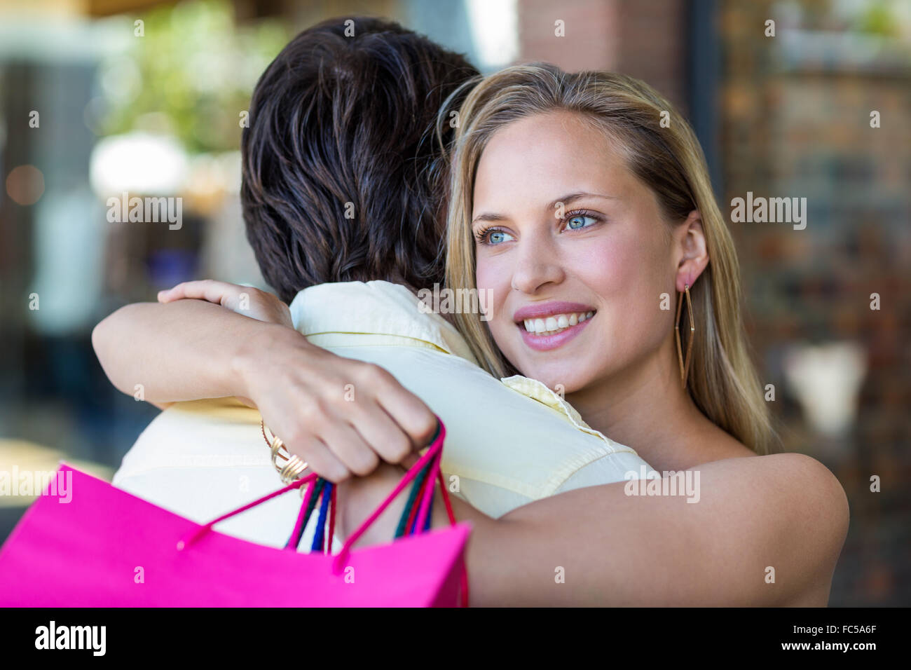 Smiling woman with shopping bags hugging her boyfriend Stock Photo - Alamy