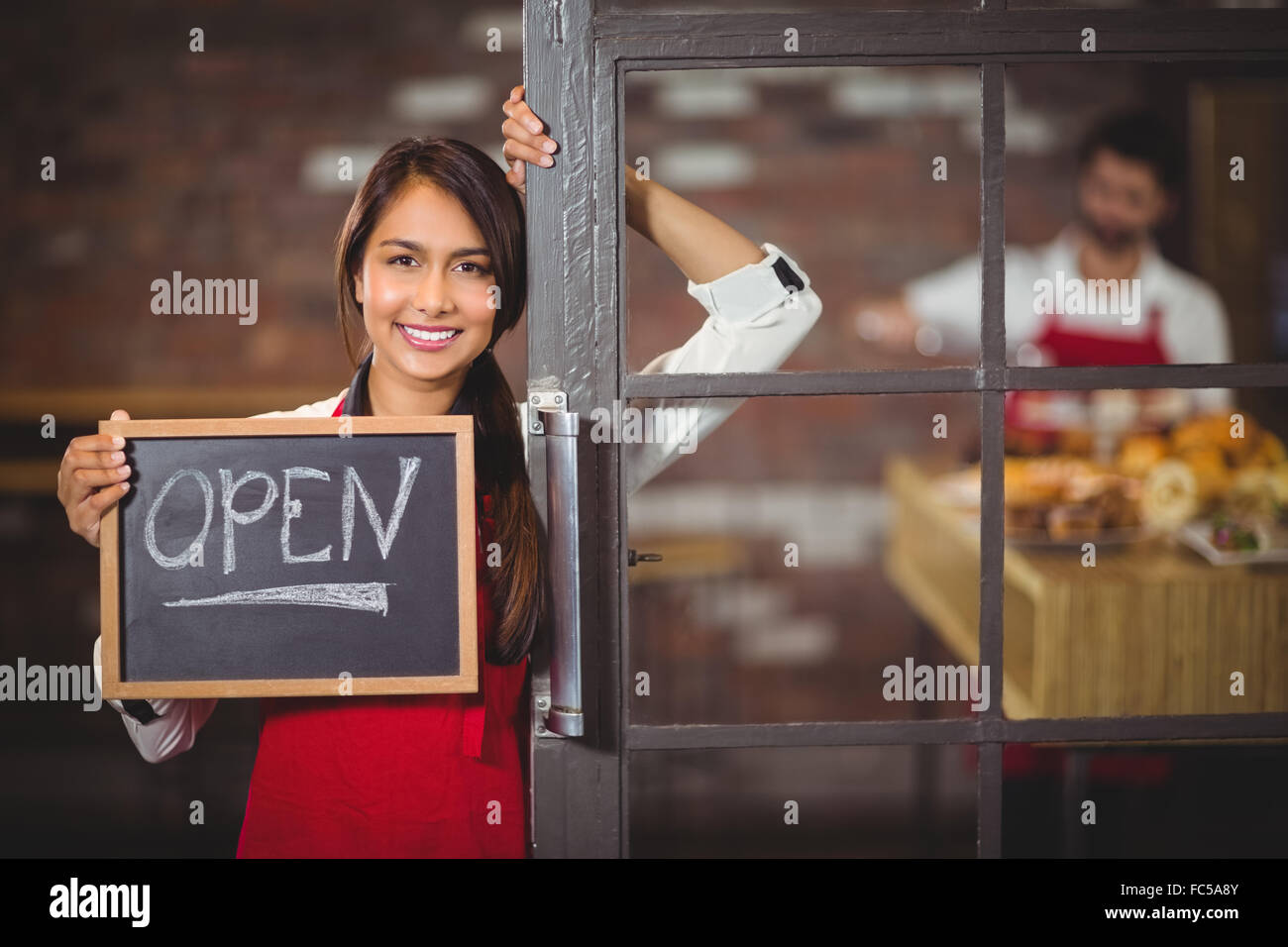 Smiling waitress showing chalkboard with open sign Stock Photo - Alamy