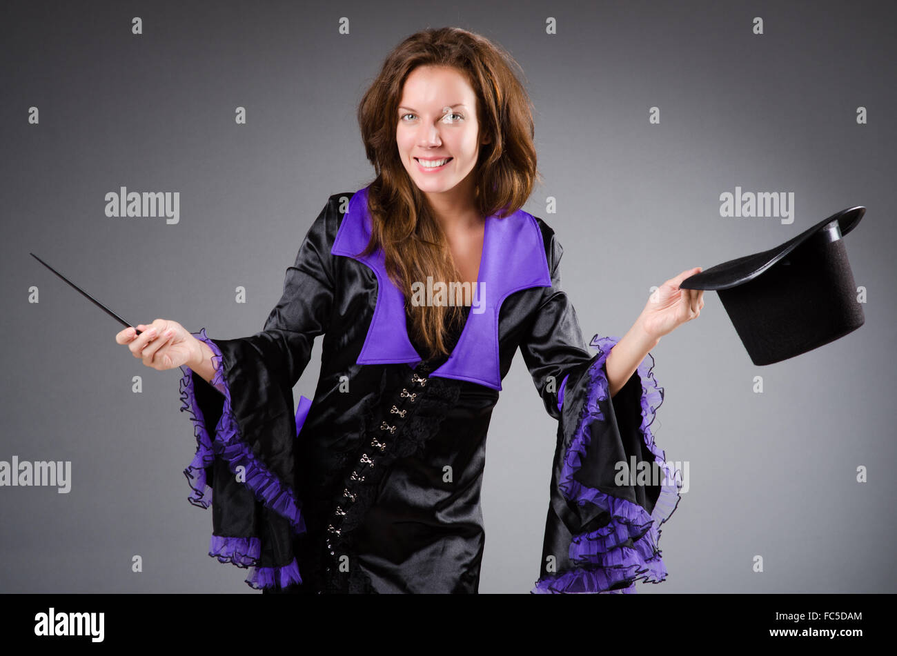Pretty magician girl holding stick against gray Stock Photo - Alamy