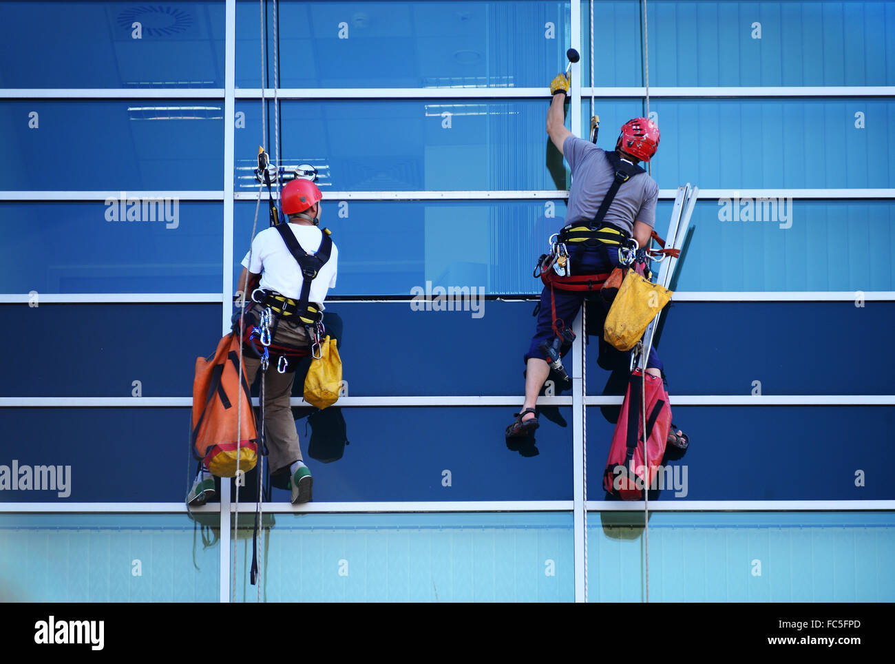 Two construction workers working at height on modern commercial ...