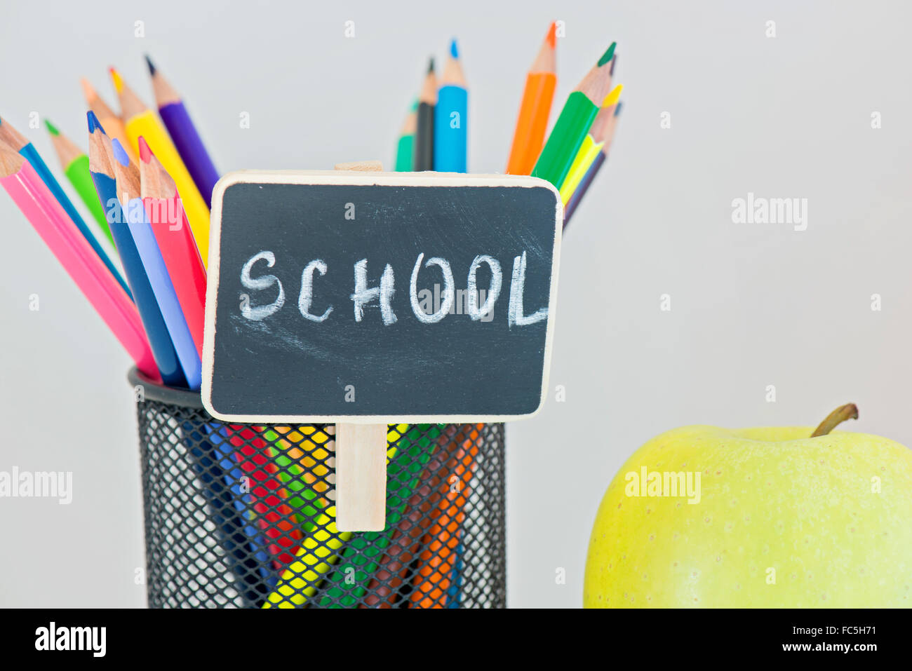 Yellow apple and pencils in holder Stock Photo - Alamy