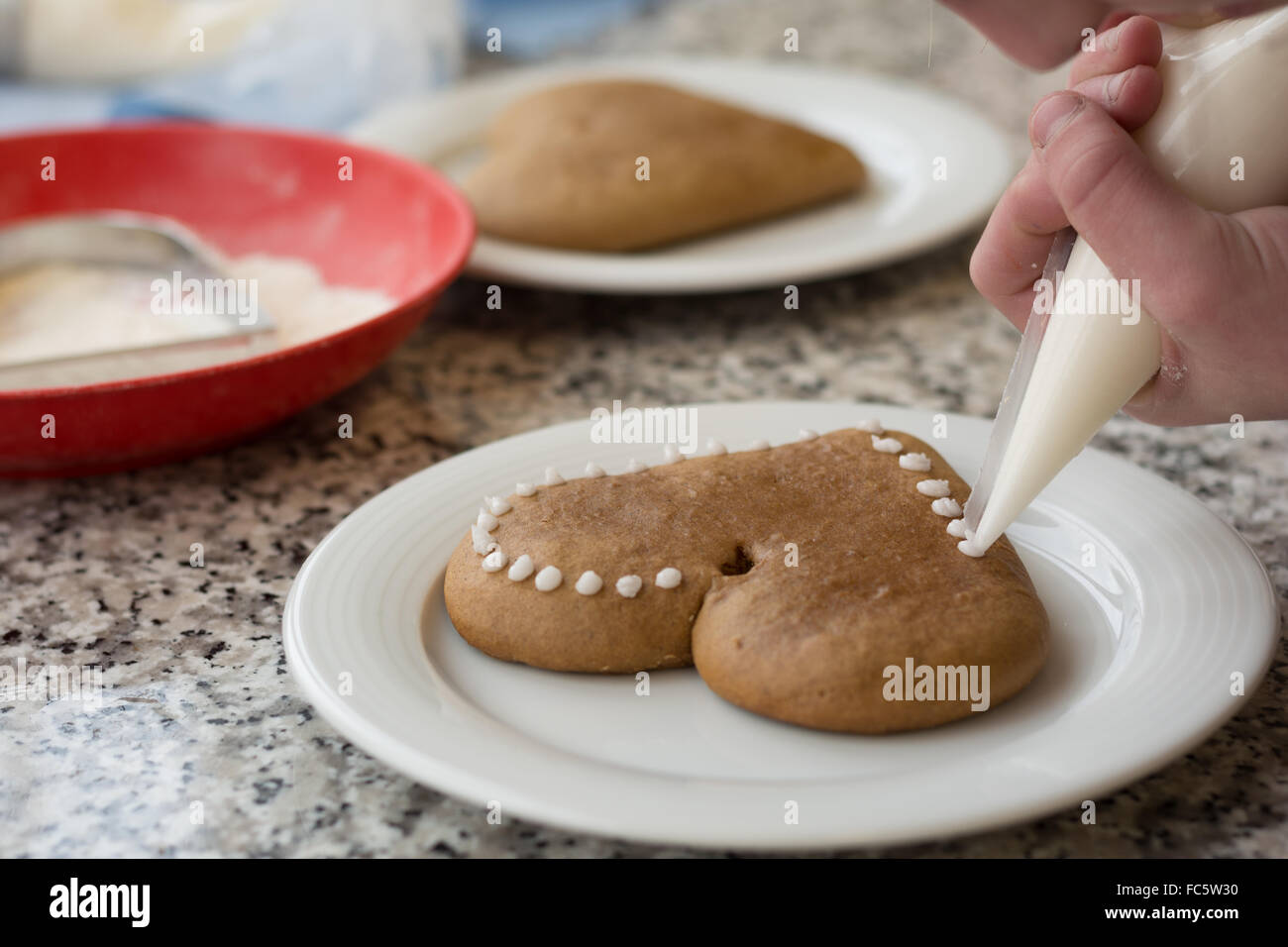 Frosting is applied to gingerbread hearts Stock Photo - Alamy