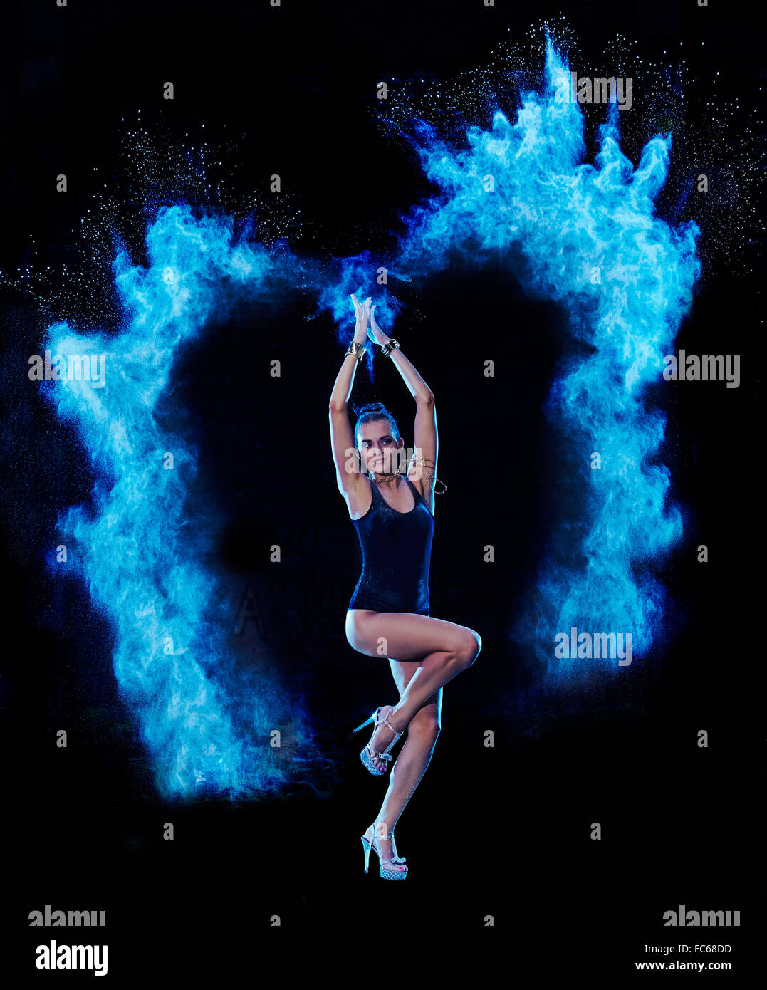 Young woman jumping in blue powder cloud Stock Photo - Alamy