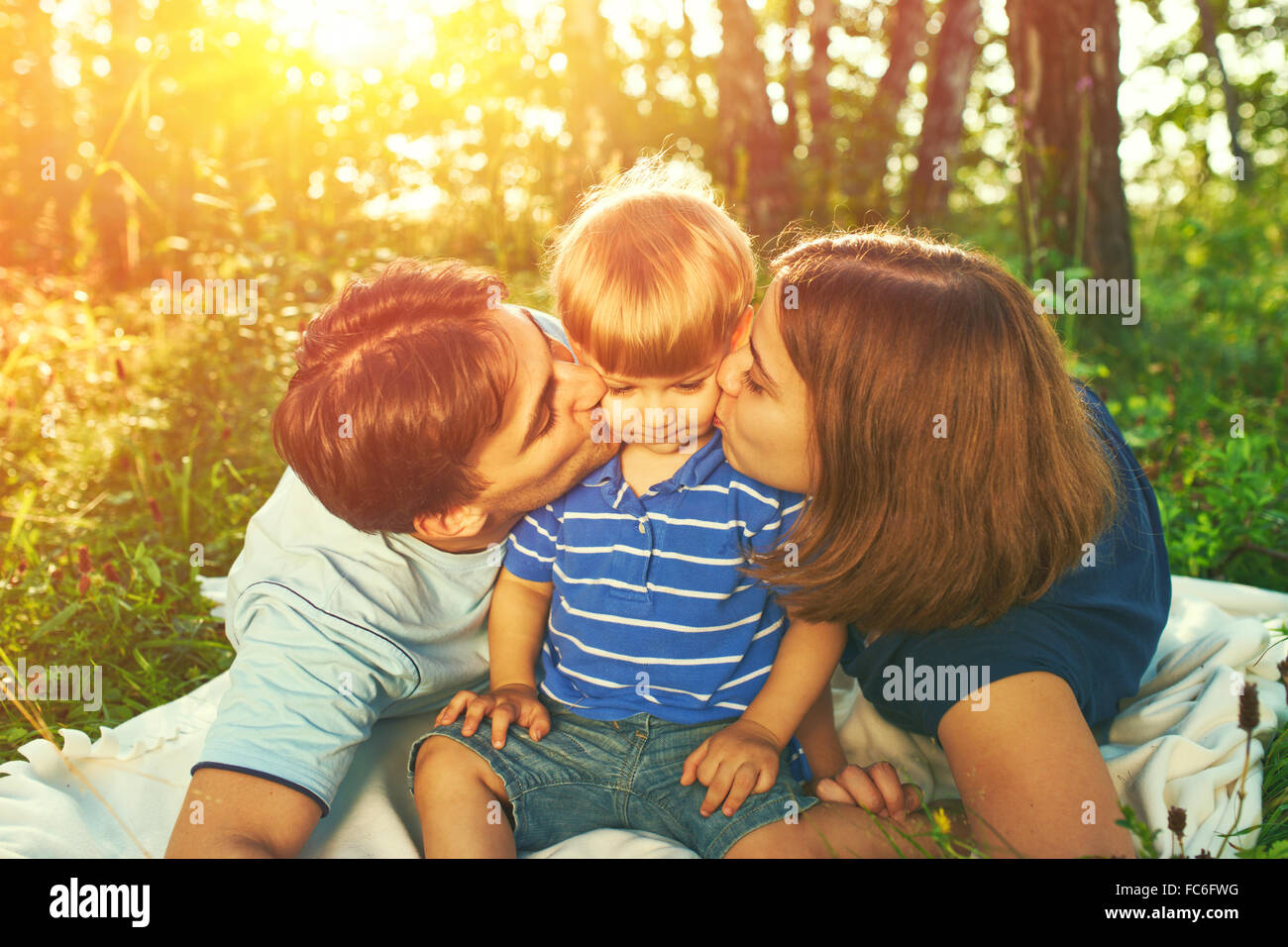 Happy parents kissing their child outdoors Stock Photo - Alamy