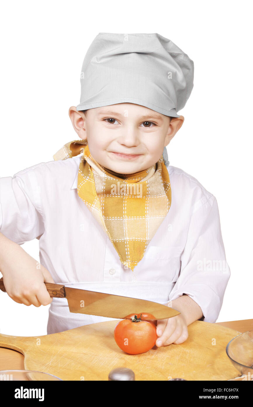 Cute little cook cutting tomato Stock Photo - Alamy