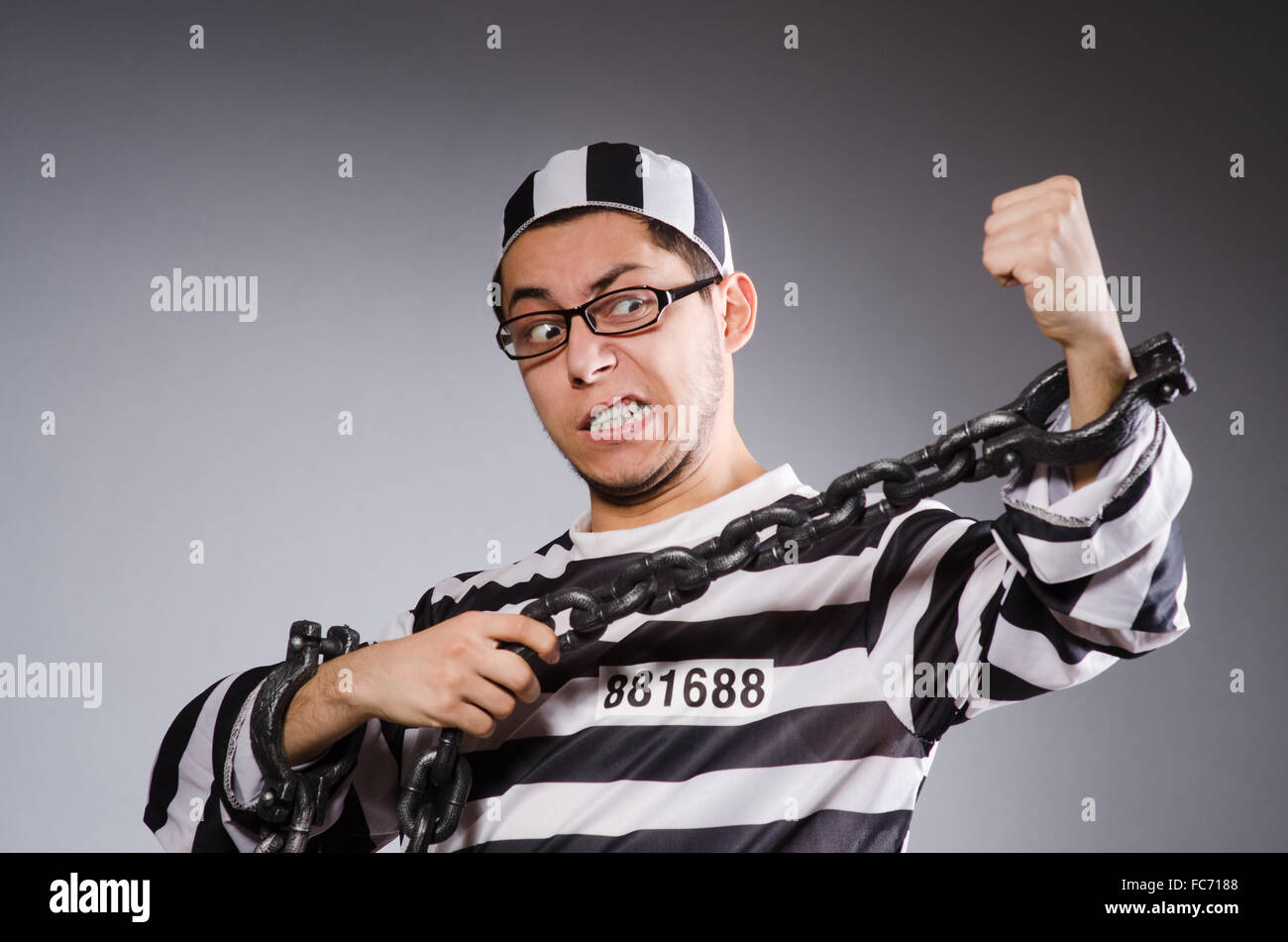 Young prisoner in chains against gray Stock Photo - Alamy