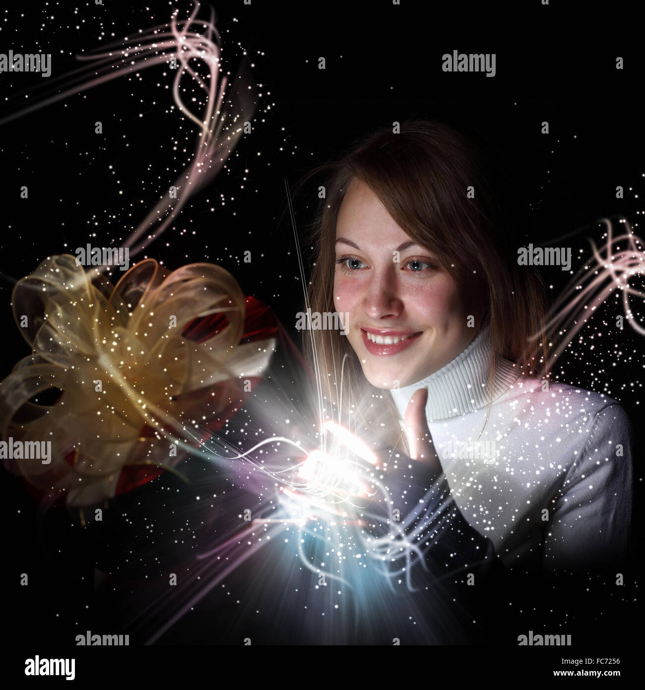 Young woman opening a gift box with shining and glittering lights ...