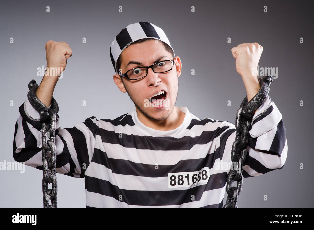 Young prisoner in chains against gray Stock Photo - Alamy