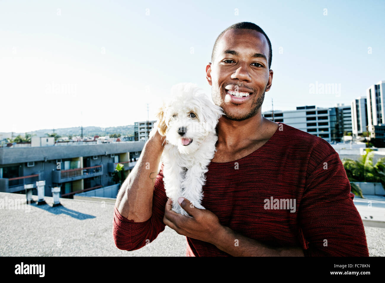 African American man holding dog on urban rooftop Stock Photo - Alamy