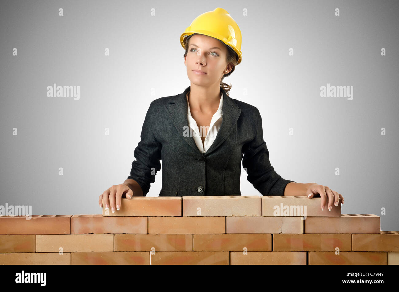 Young female builder near brick wall Stock Photo - Alamy