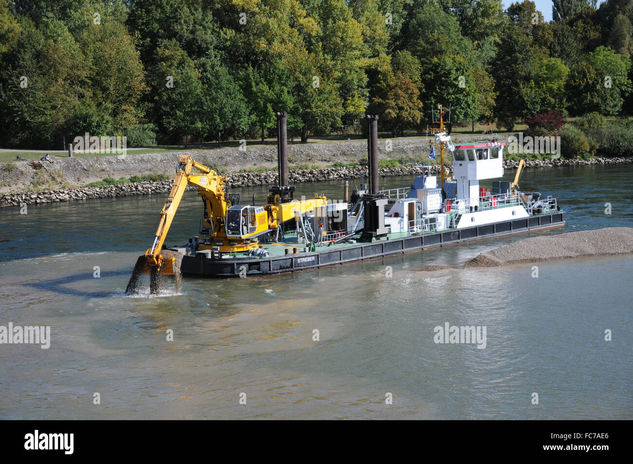 Excavator on a ship digging pebbles Stock Photo - Alamy