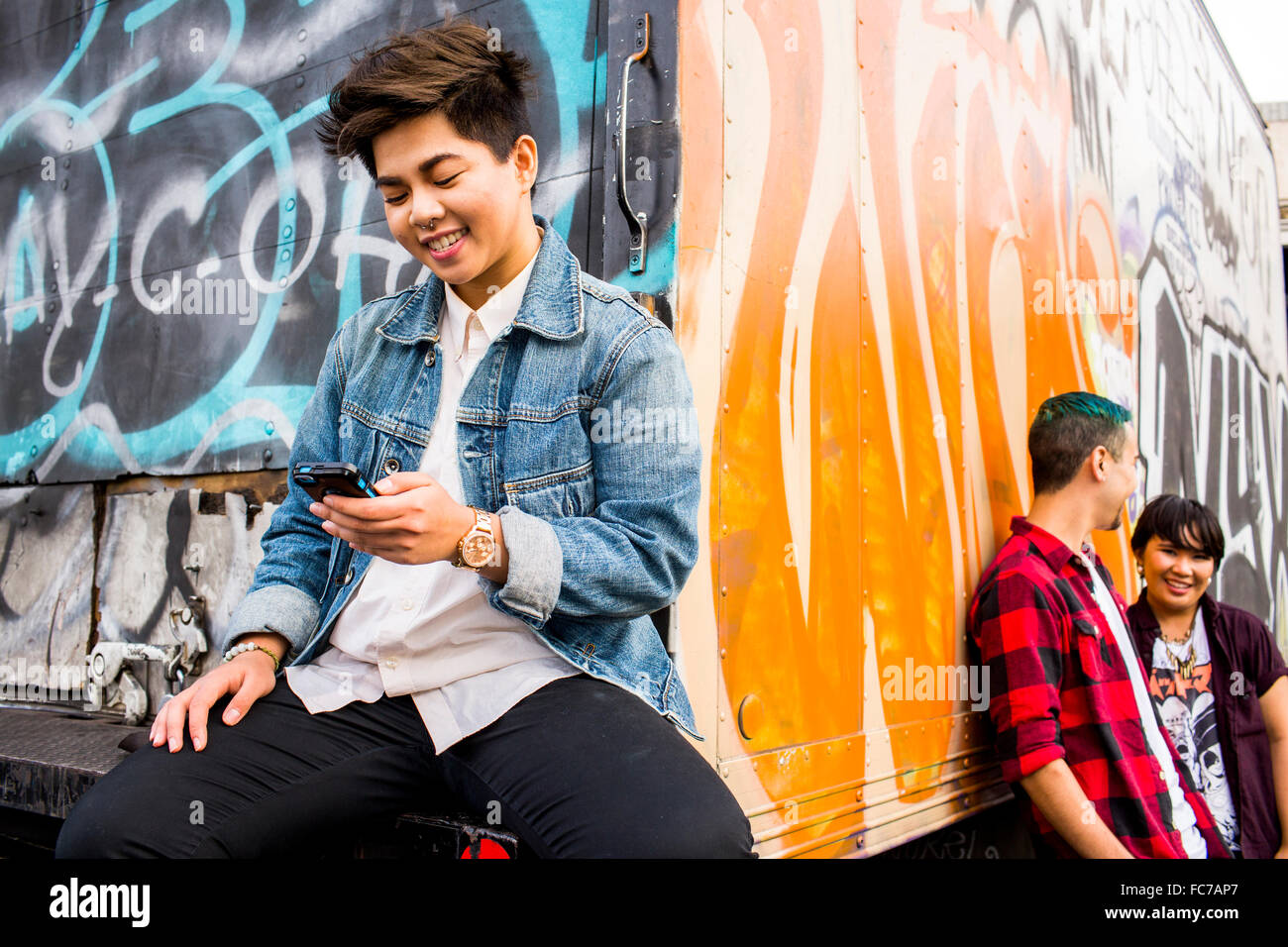Woman using cell phone at graffiti truck Stock Photo - Alamy