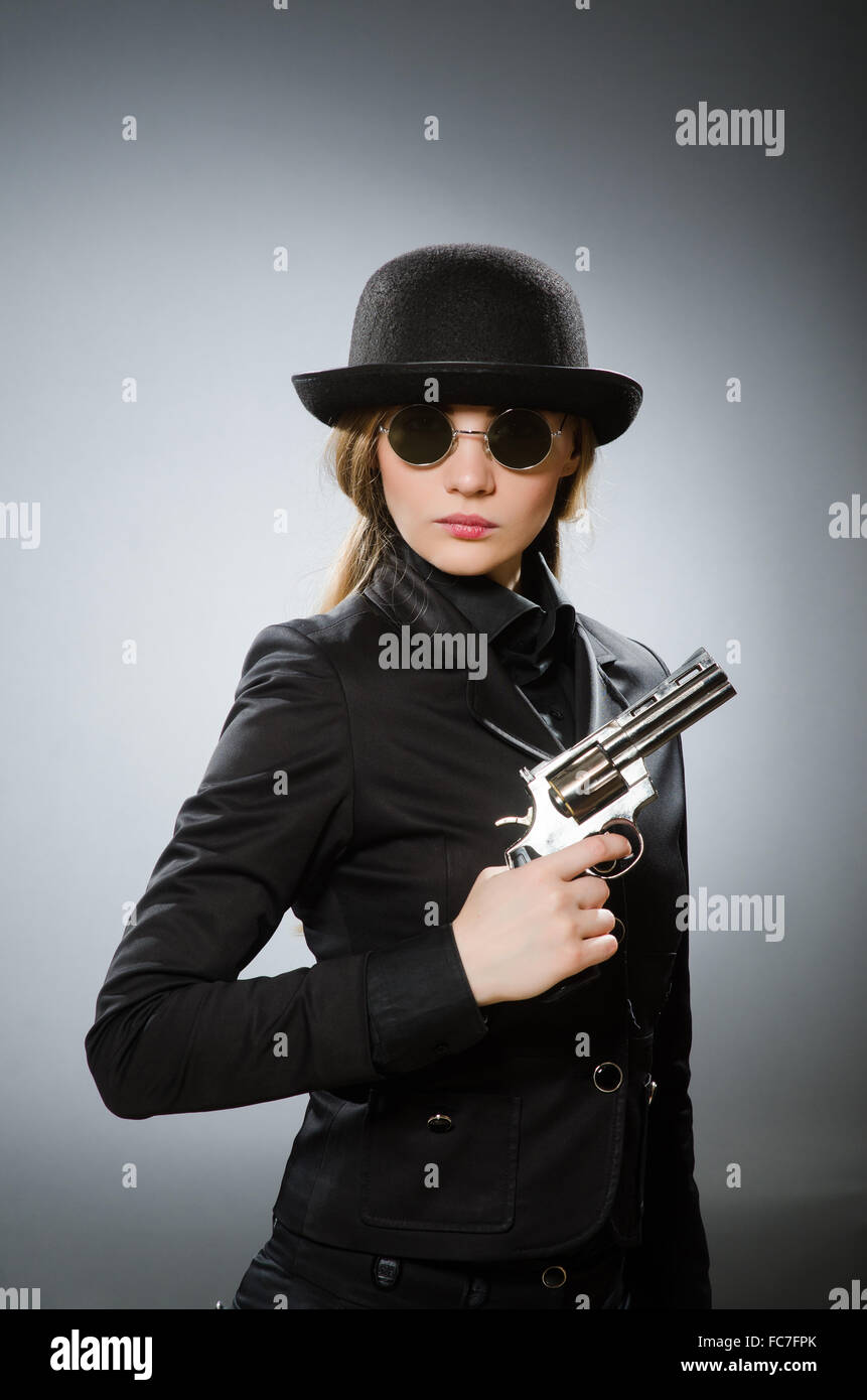Female spy with weapon against gray Stock Photo - Alamy